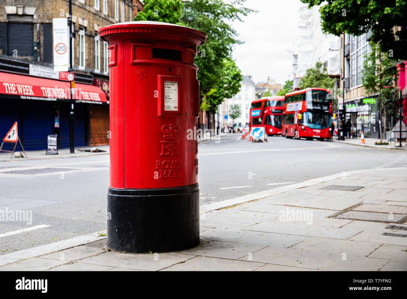 Exterior Red Royal Mail Pillar Post Box on street. Red bunk buses in ...