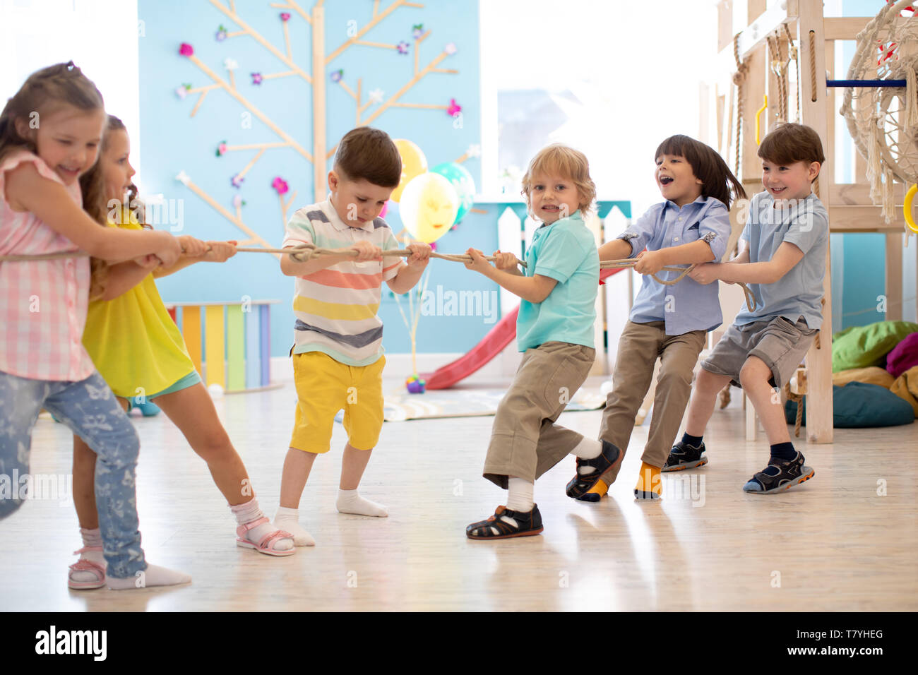 group of preschool kids play and pull rope together in daycare Stock ...