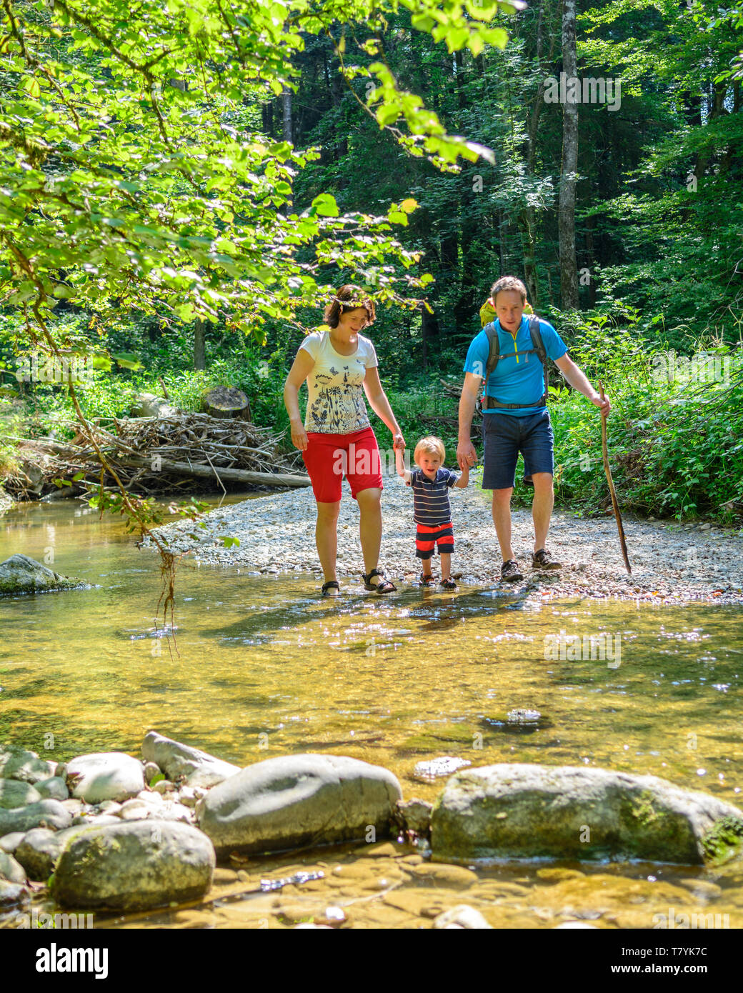 Young family with a cute boy exploring a riverbed at a hot summer day ...