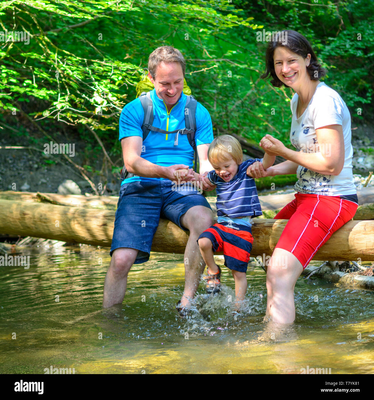 Young family with a cute boy exploring a riverbed at a hot summer day ...