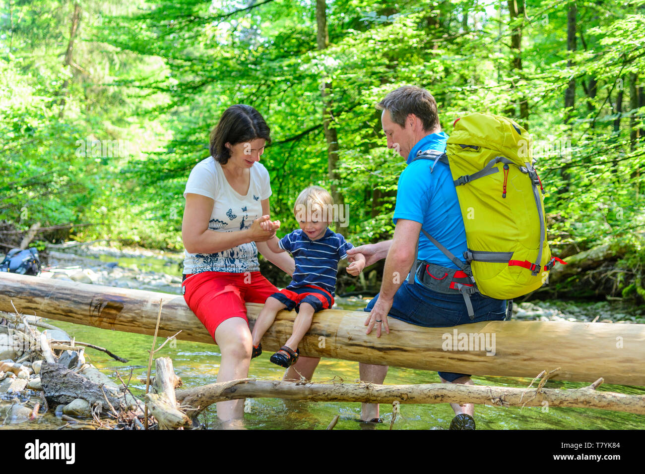 Young family with a cute boy exploring a riverbed at a hot summer day ...