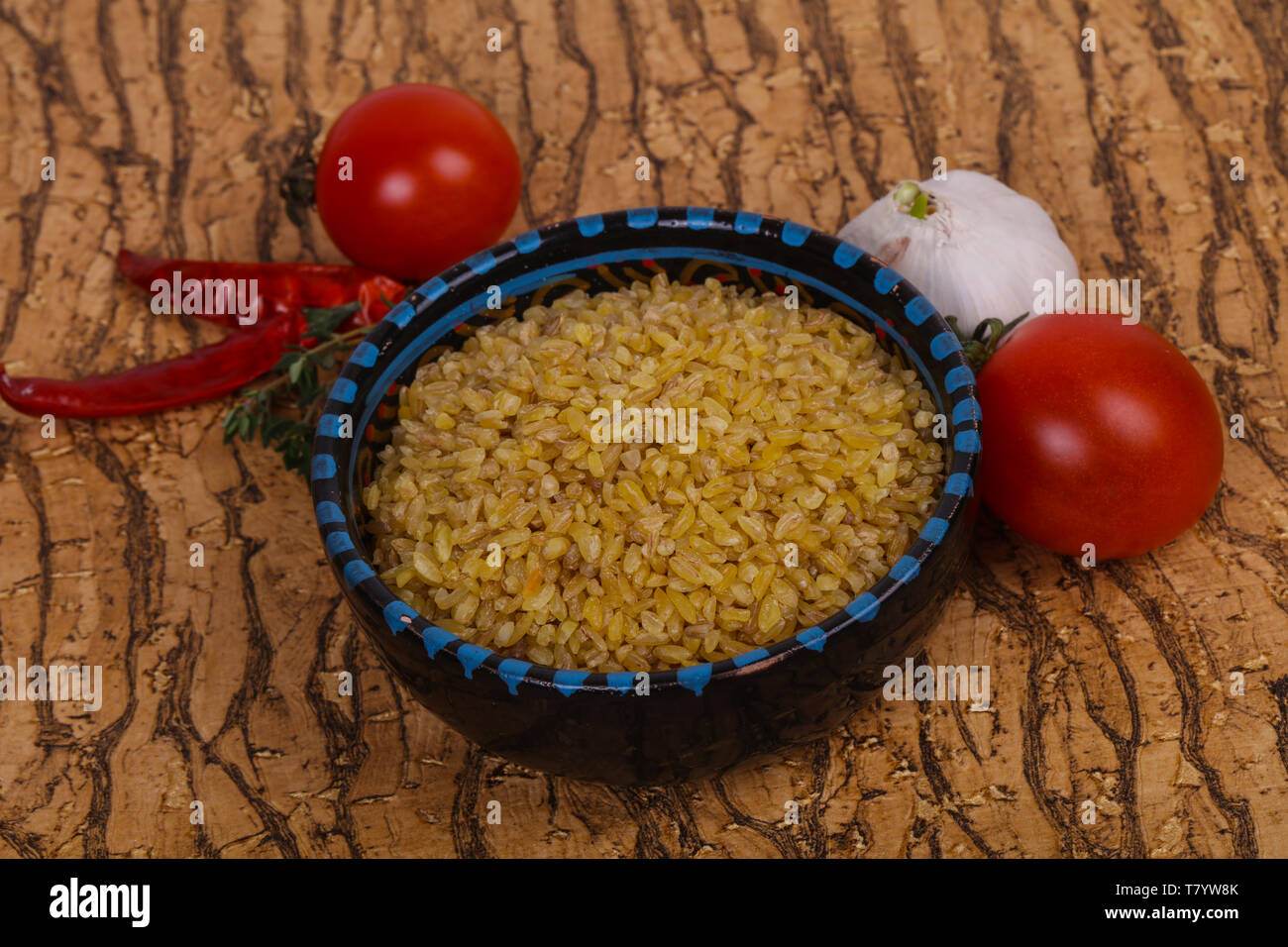 Raw golden bulgur in the bowl with tomatoes and garlic Stock Photo - Alamy