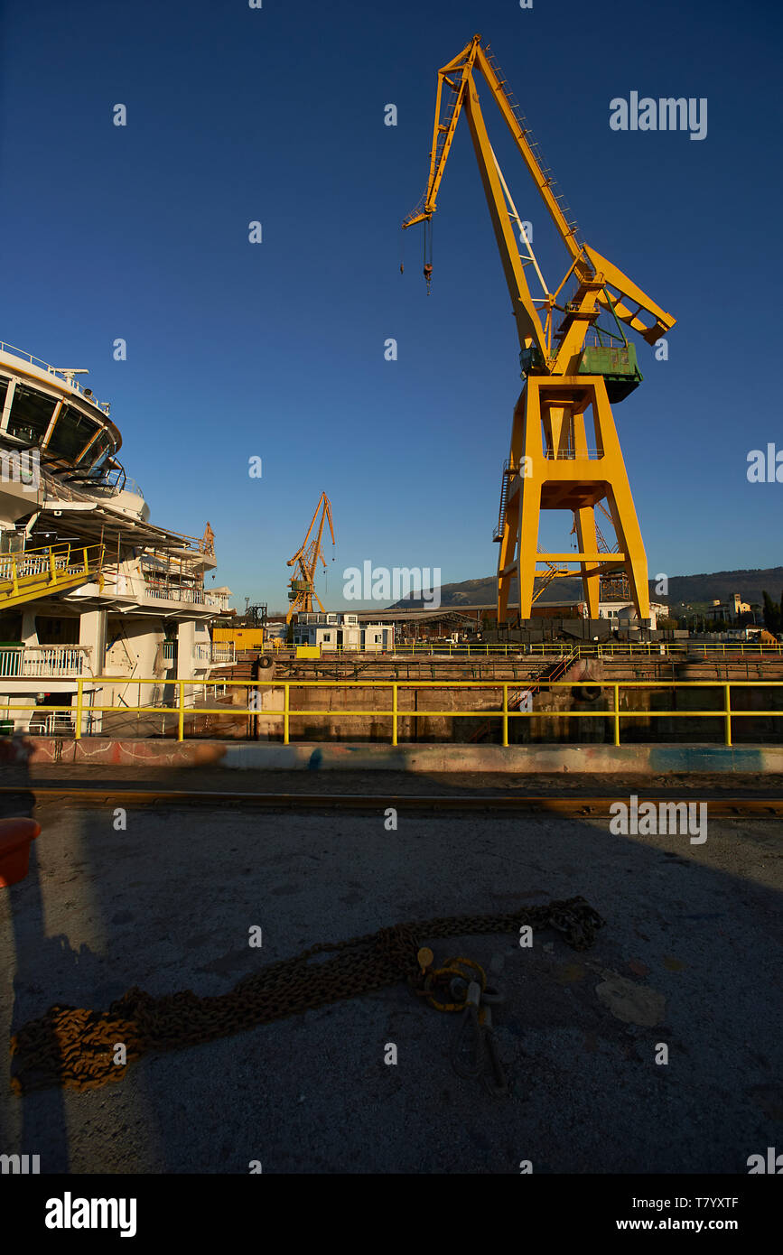 Shipyard with cranes and a newly constructed ship in summer sunshine ...