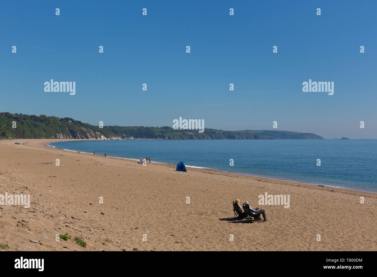 Slapton Sands beach Devon England UK with couple sitting in deckchairs ...