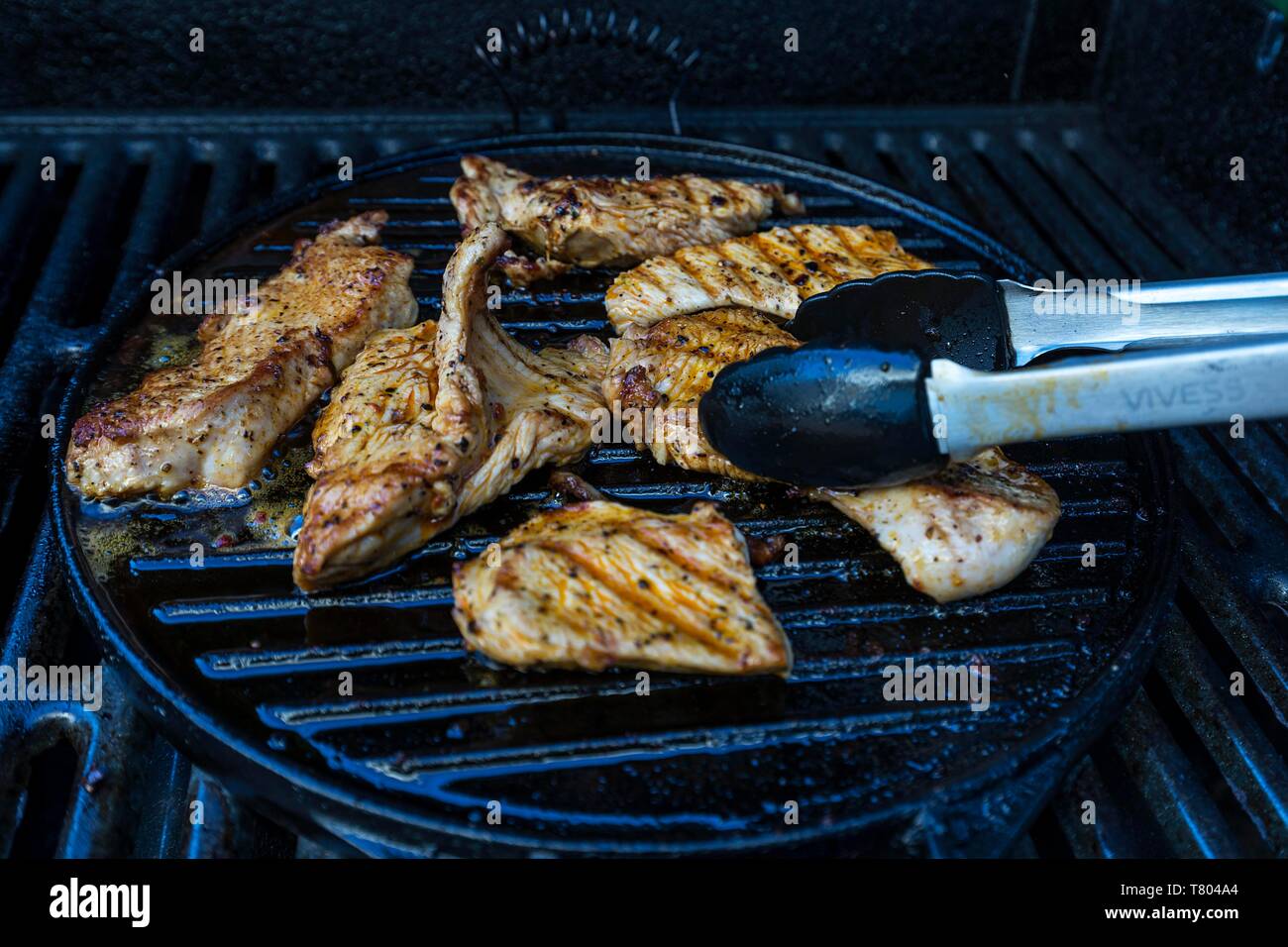 Grilled turkey meat, turkey steaks on the grill, with barbecue tong ...