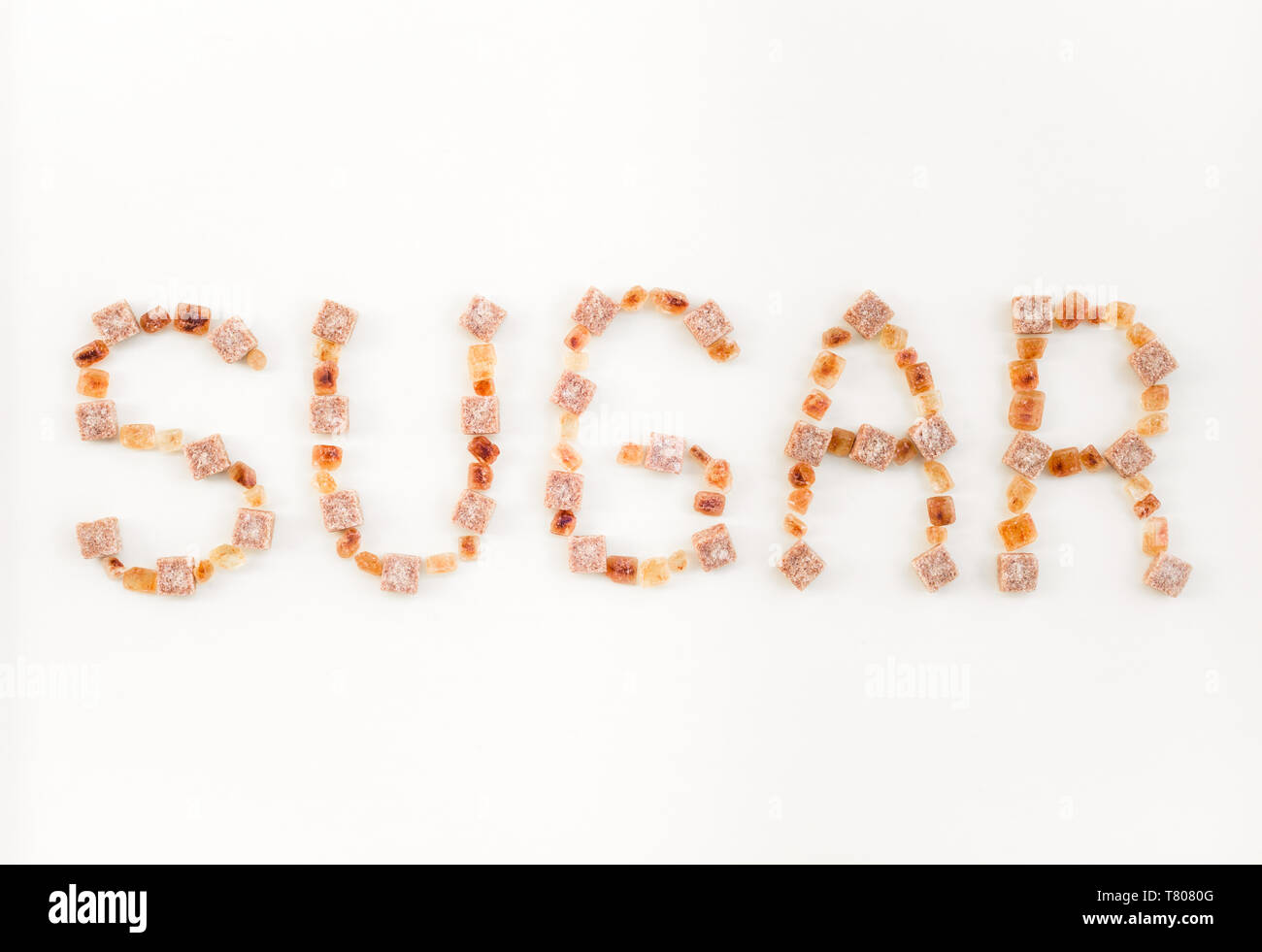 The word SUGAR written with brown sugar pieces, on white background ...