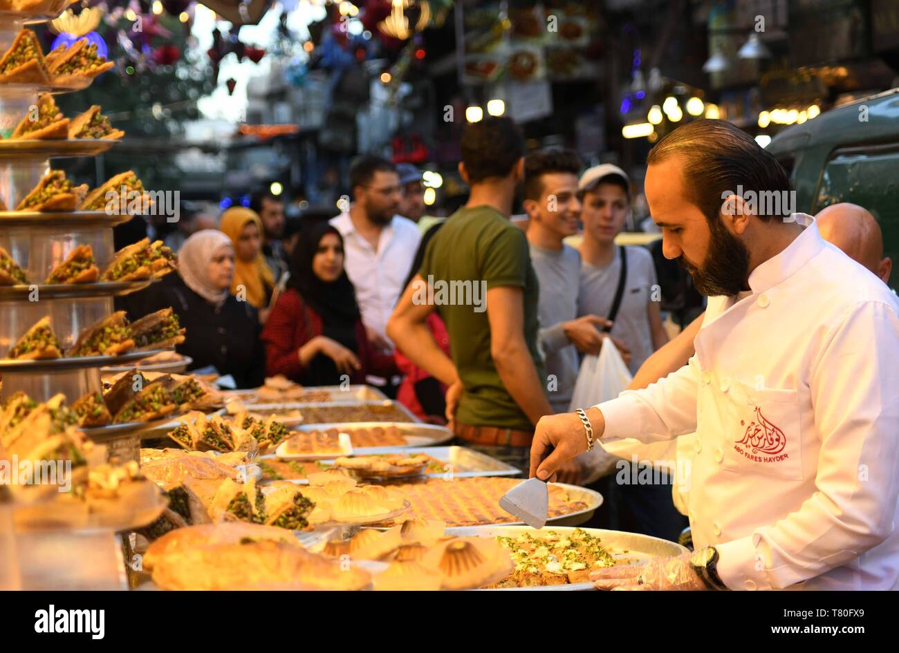 Damascus, Syria. 9th May, 2019. A Syrian sweet shop worker arranges ...