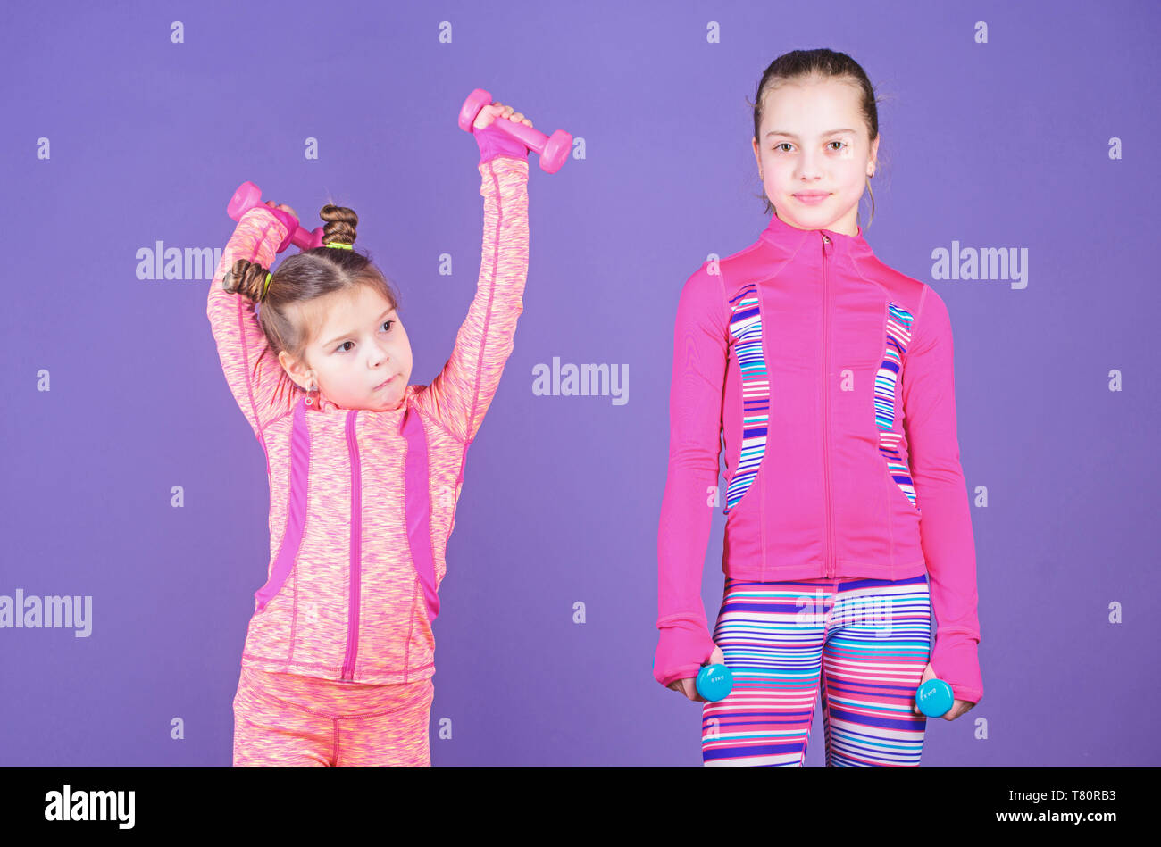 Following her sister. Girls cute kid exercising with dumbbells ...
