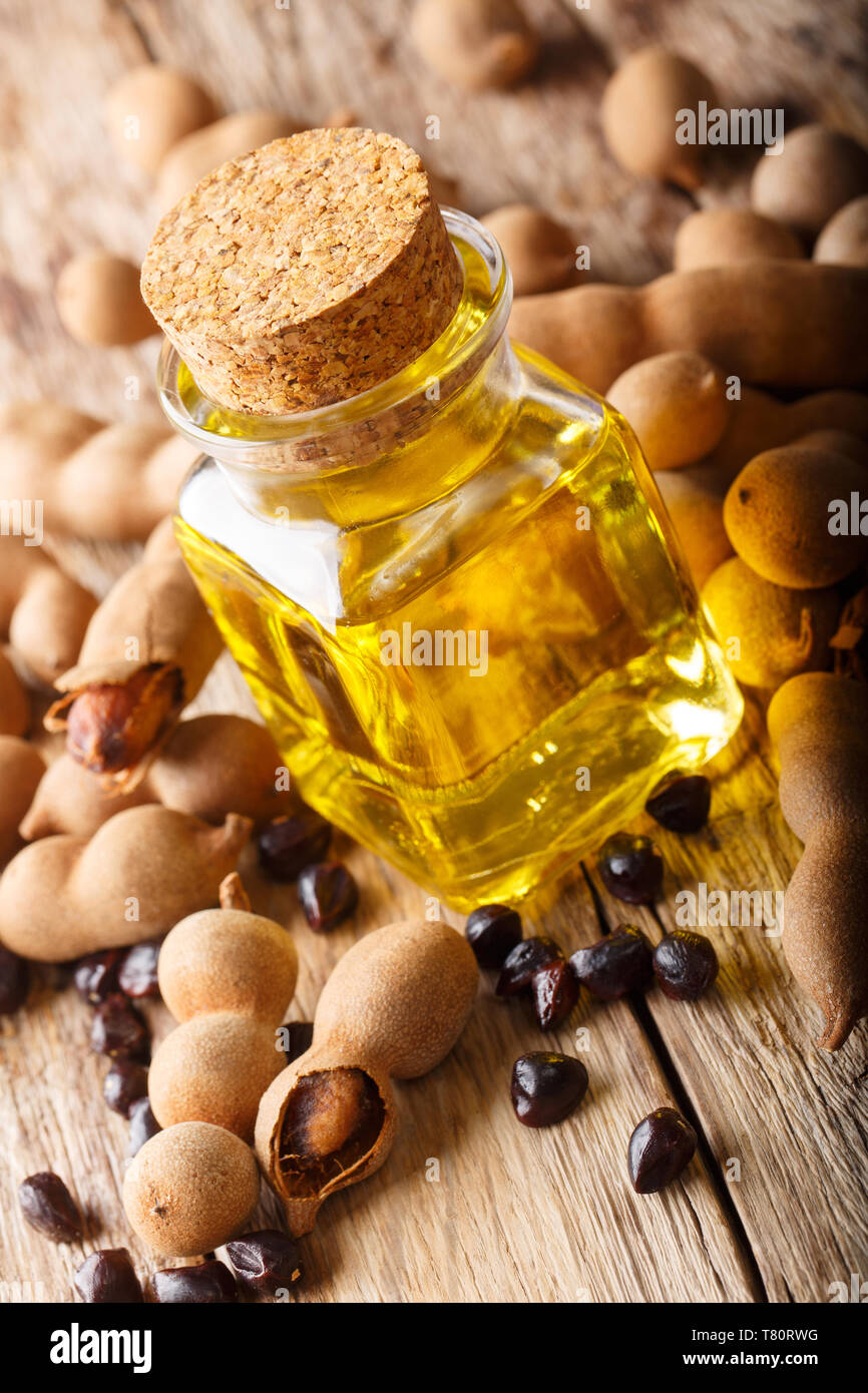 Tamarind seed oil in a glass jar closeup and ingredients on a wooden ...