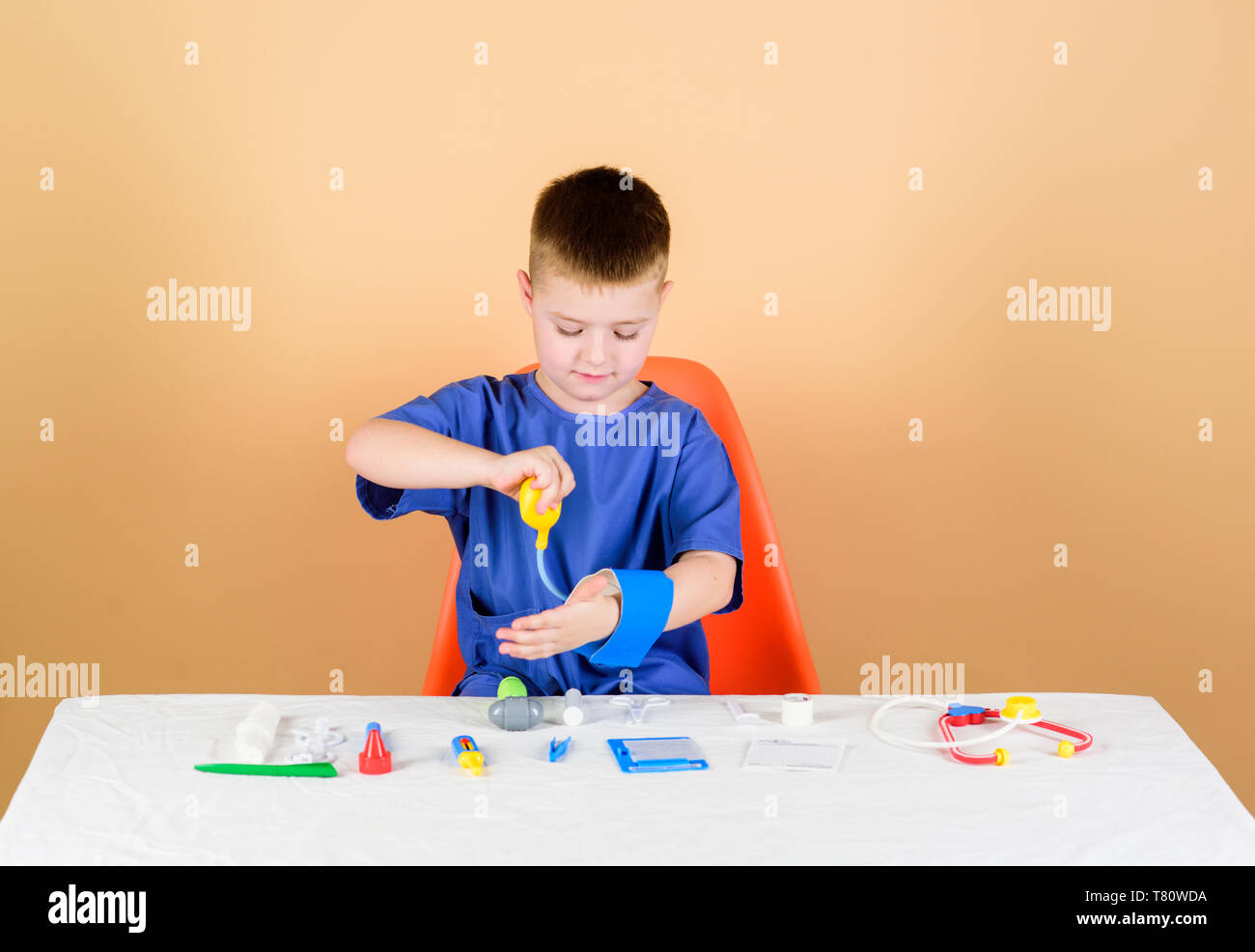 Kid little doctor sit table with stethoscope and medical tools ...