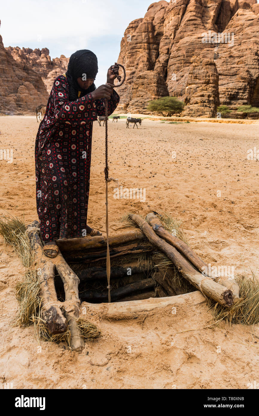 Bedouins pulling water in a beautiful rock amphitheatre in the Ennedi ...