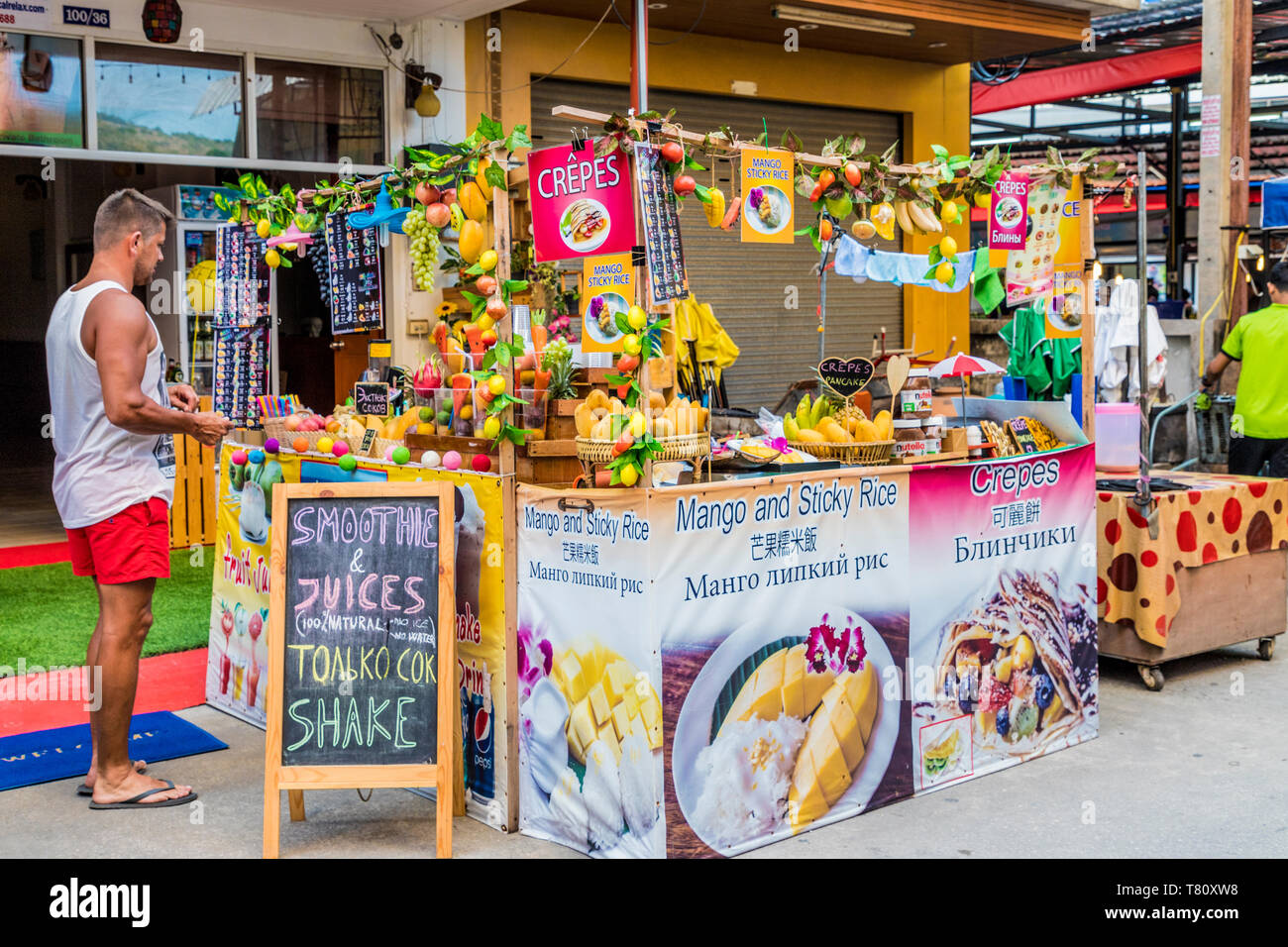 A tourist at a colourful pancake stall in Kata, Phuket, Thailand ...