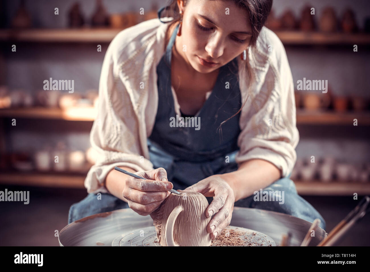 Beautiful artisan sculptor works with clay on a Potter's wheel and at ...