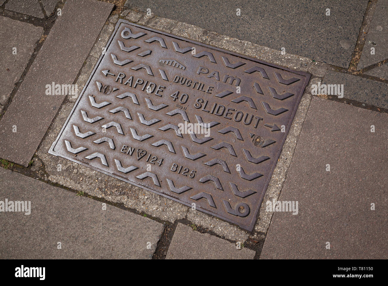 A cast-iron manhole cover marked 'Rapide 40 Slideout', 'Ductile' and ...
