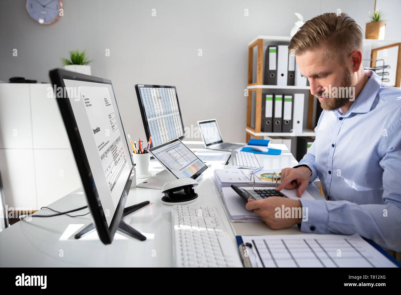Businessperson Calculating Invoice With Computer On Desk Stock Photo ...