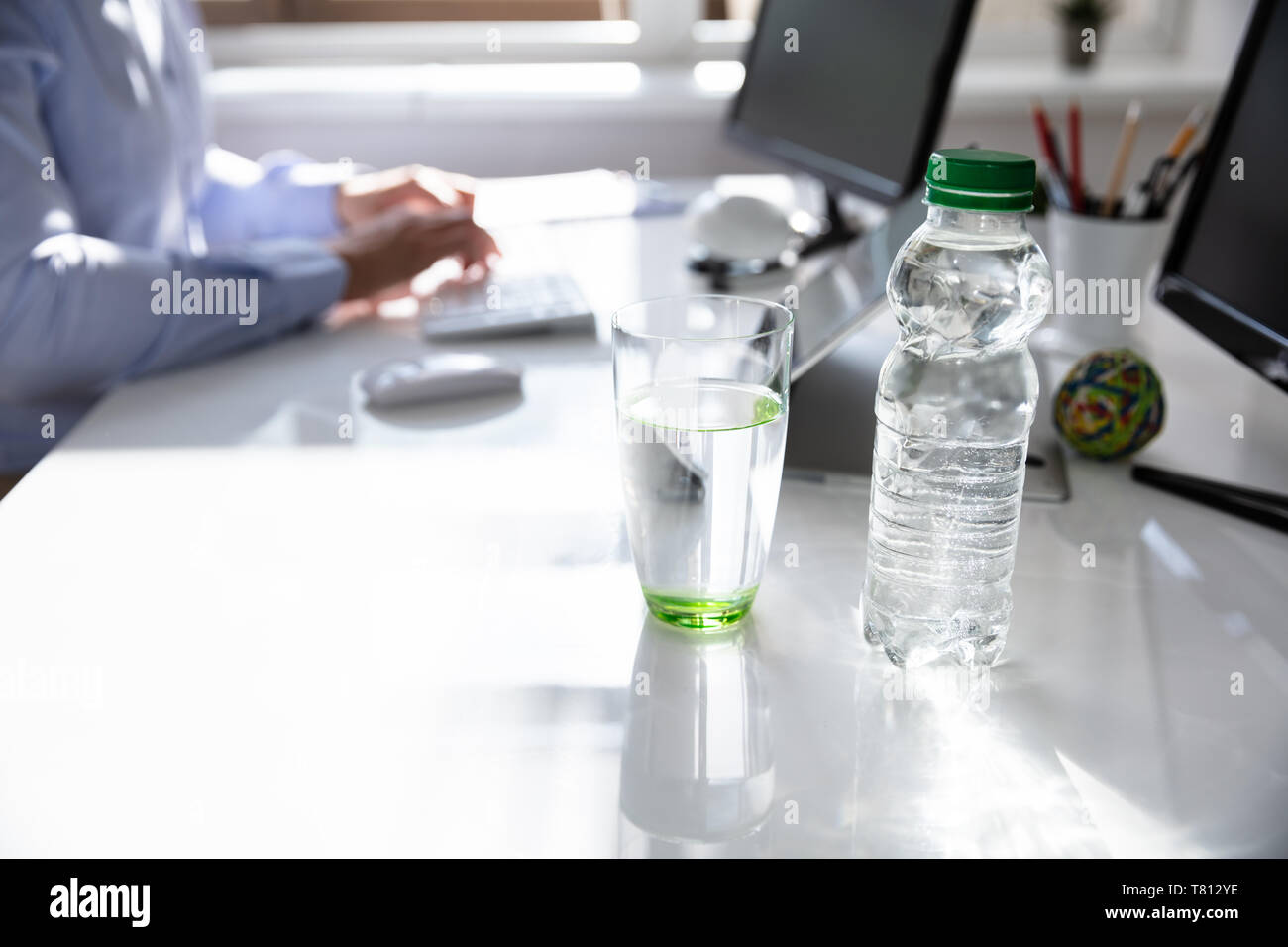Water Bottle And Drinking Glass On Desk And Man In Background Using ...