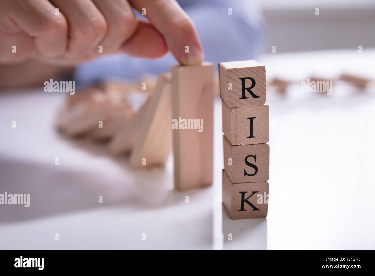 Businessperson's Finger Over Risk Wooden Blocks Stopping Dominos From ...