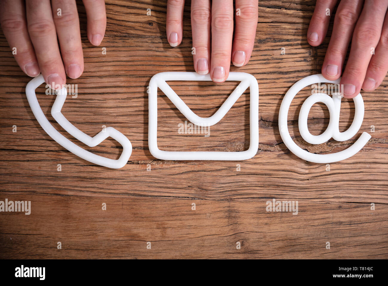 Close-up Of A People's Hand Pointing At Various Contact Icons On Wooden ...