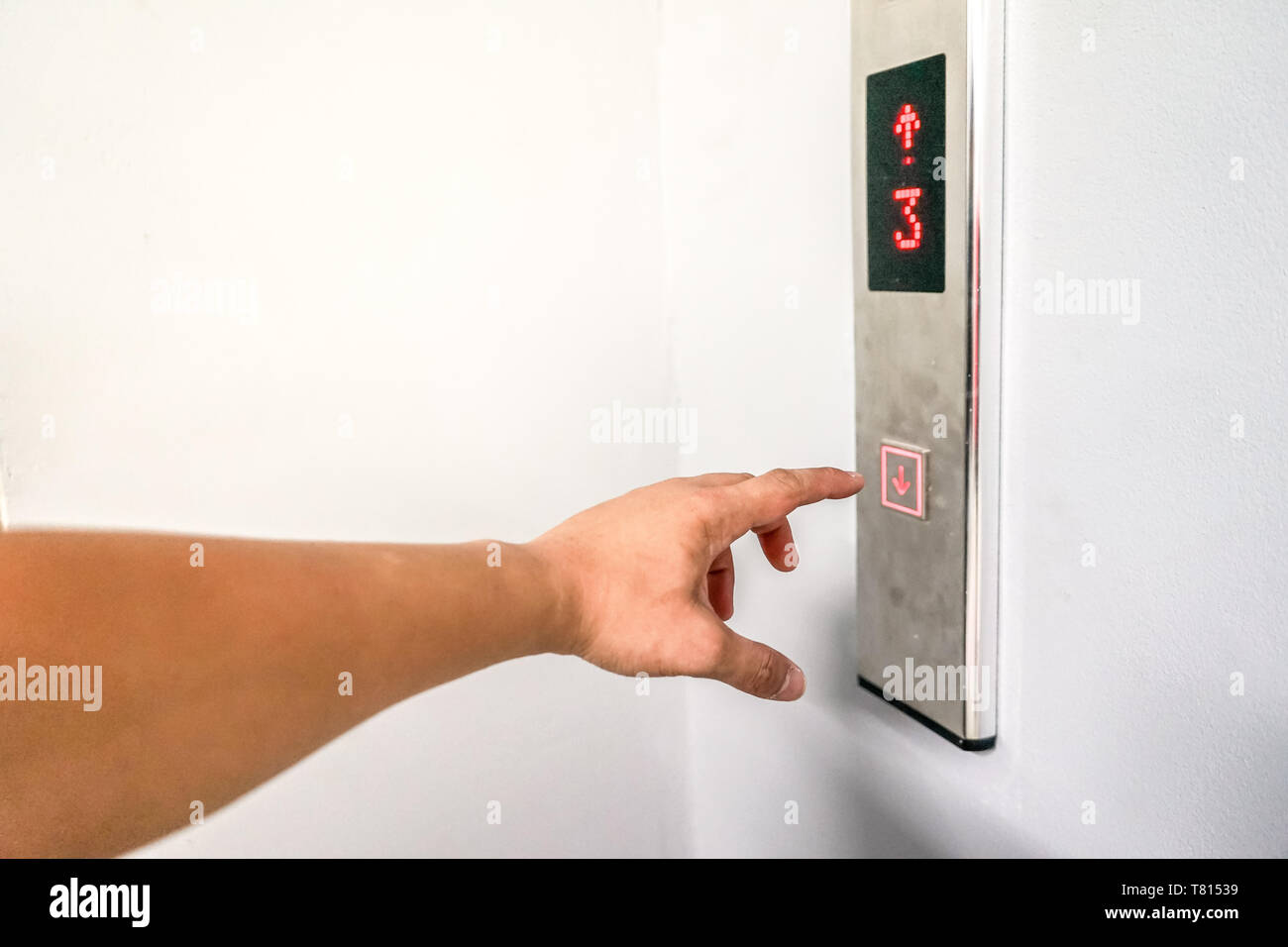 male's hand pushs the down bottom on the dirty loading elevator that's ...