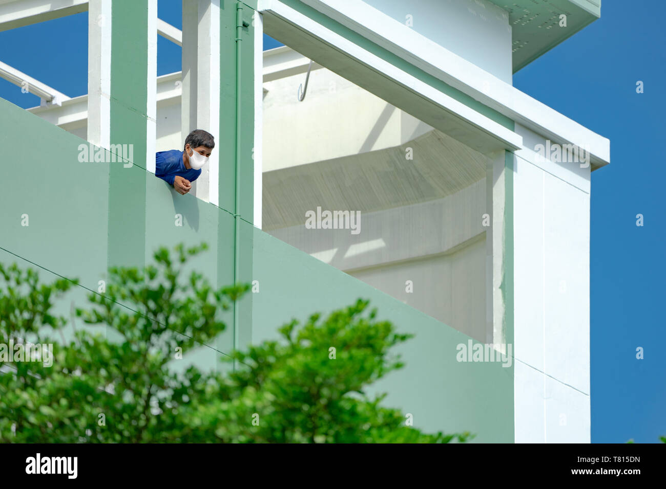 Asian labor lean out from the top of the green building which under ...