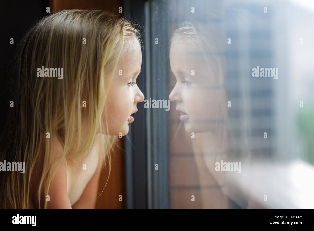 Beautiful little girl with blonde hair looking into a window Stock ...