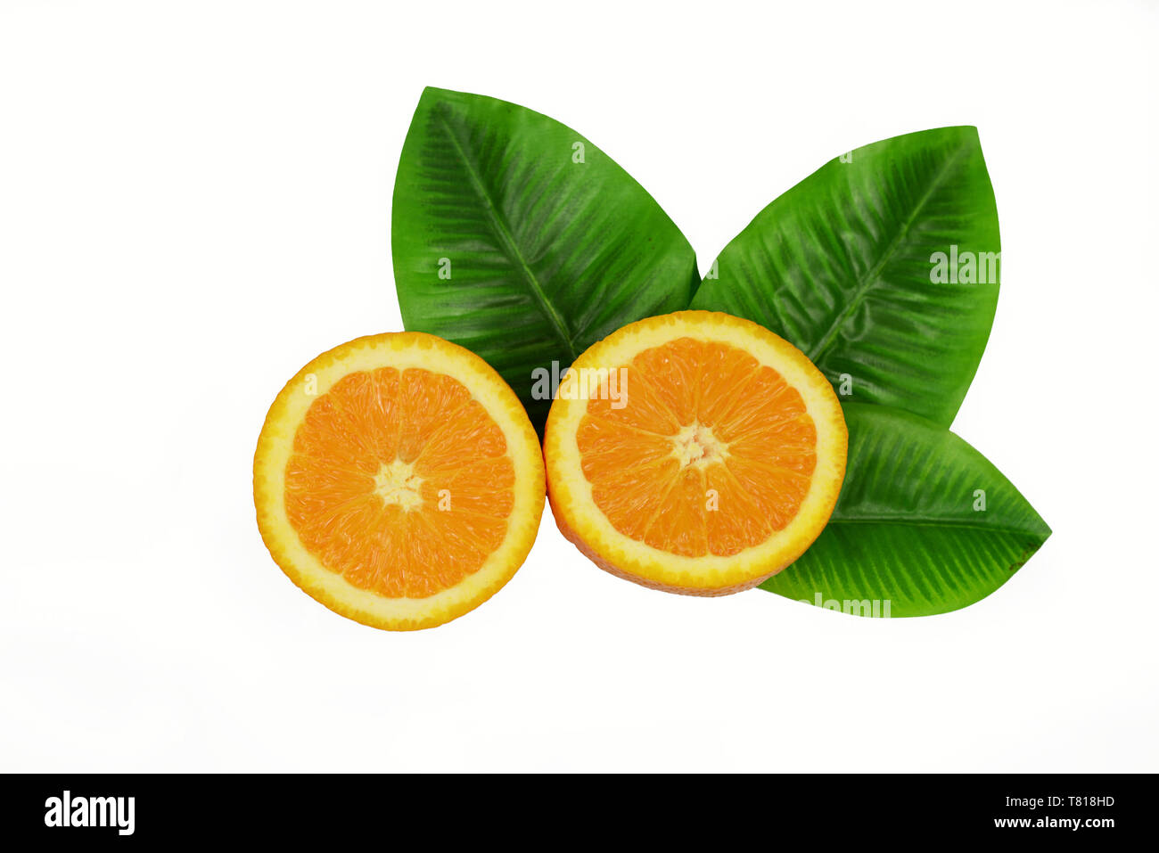two half ripe orange fruit useful with leaf on an isolated white ...