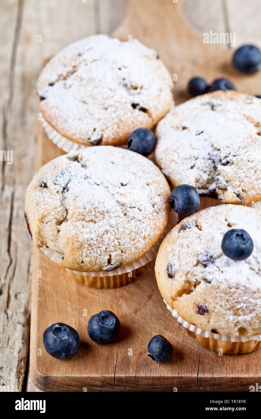 Four homemade fresh muffins with blueberries on rustic wooden table ...