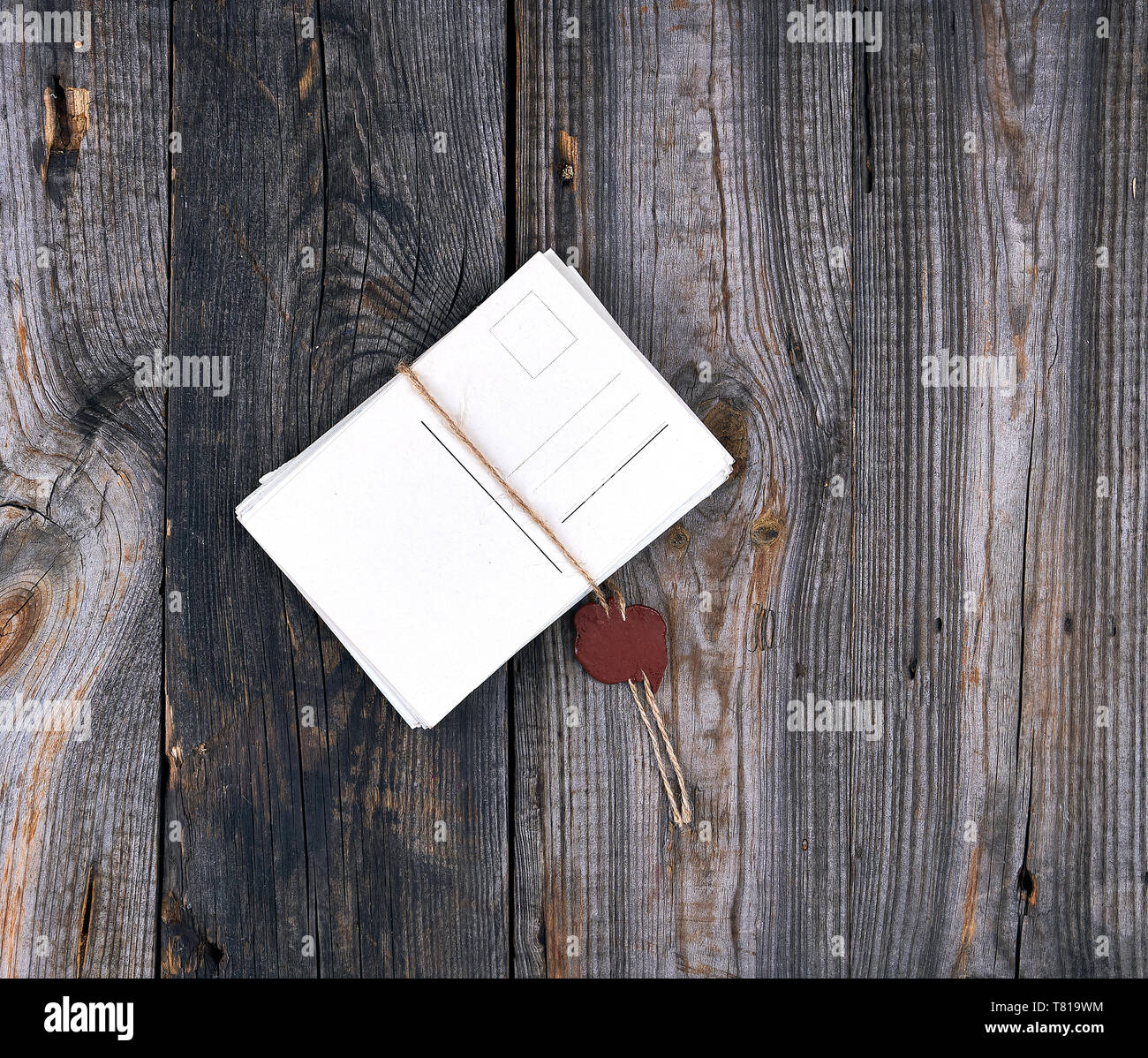 stack of paper cards tied with a rope with a stamp on a gray old wooden ...
