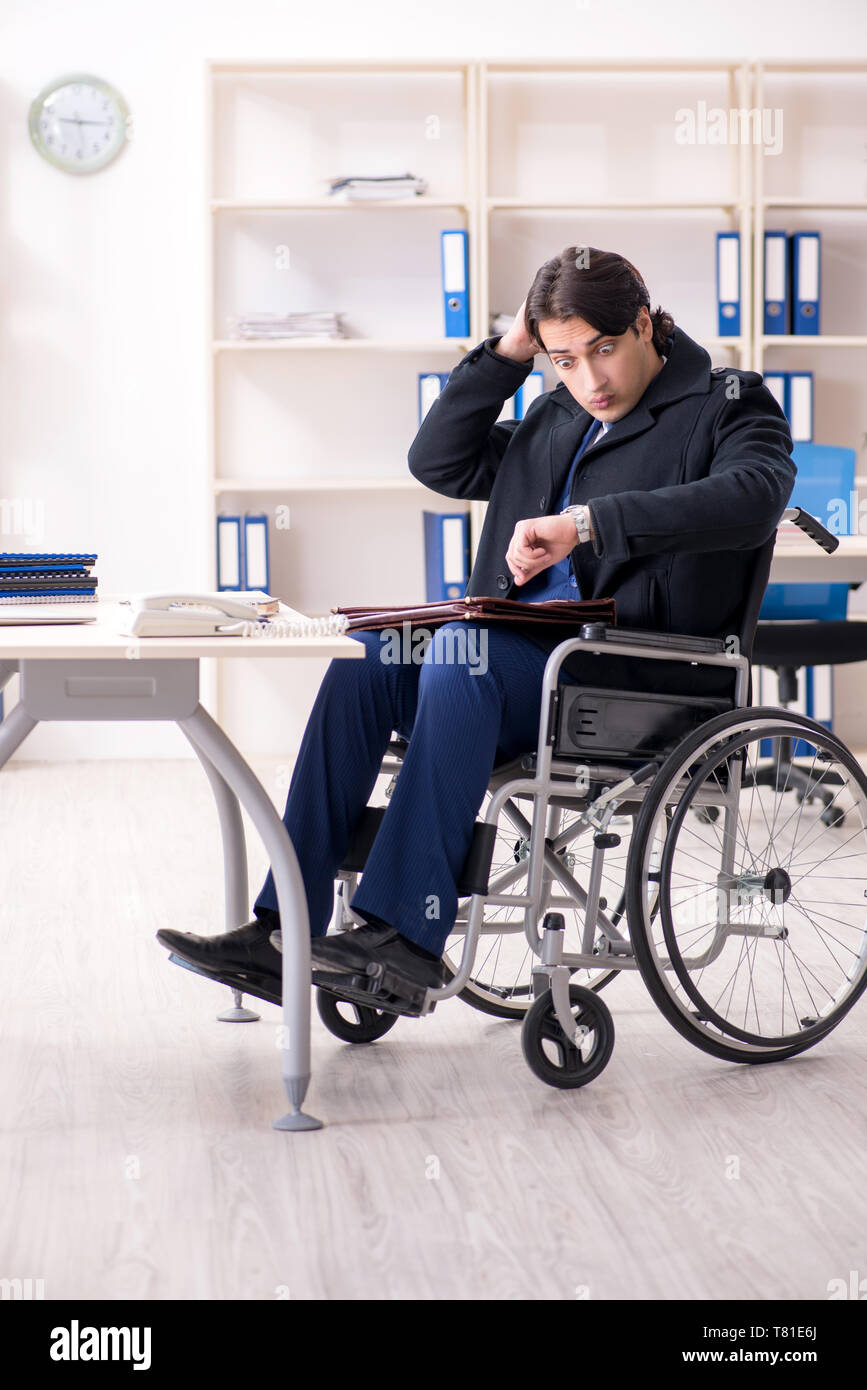 Young male employee in wheelchair working in the office Stock Photo - Alamy