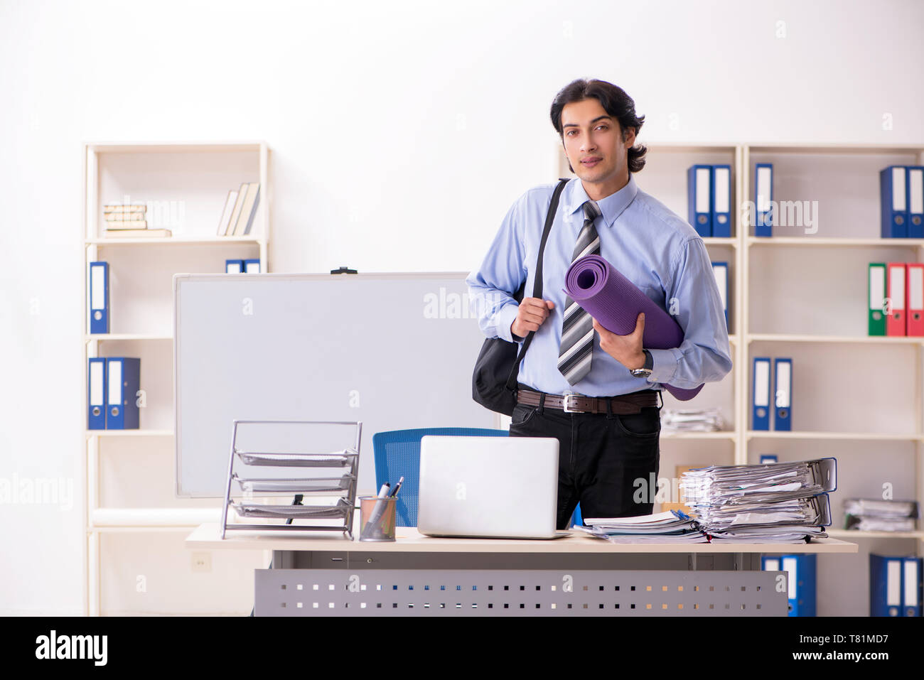Young handsome male employee doing exercises in the office Stock Photo ...