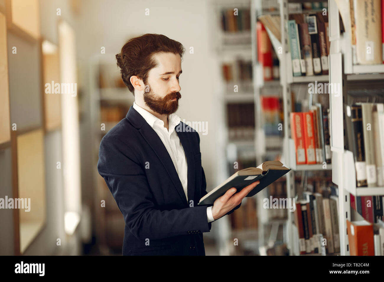Man in a library. Guy in a black suit. Student with a books Stock Photo ...