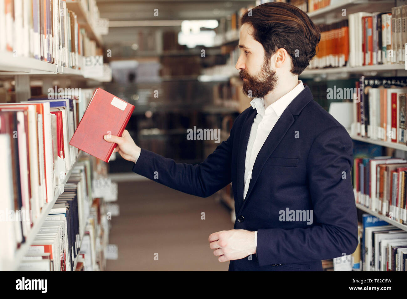 Man in a library. Guy in a black suit. Student with a books Stock Photo ...