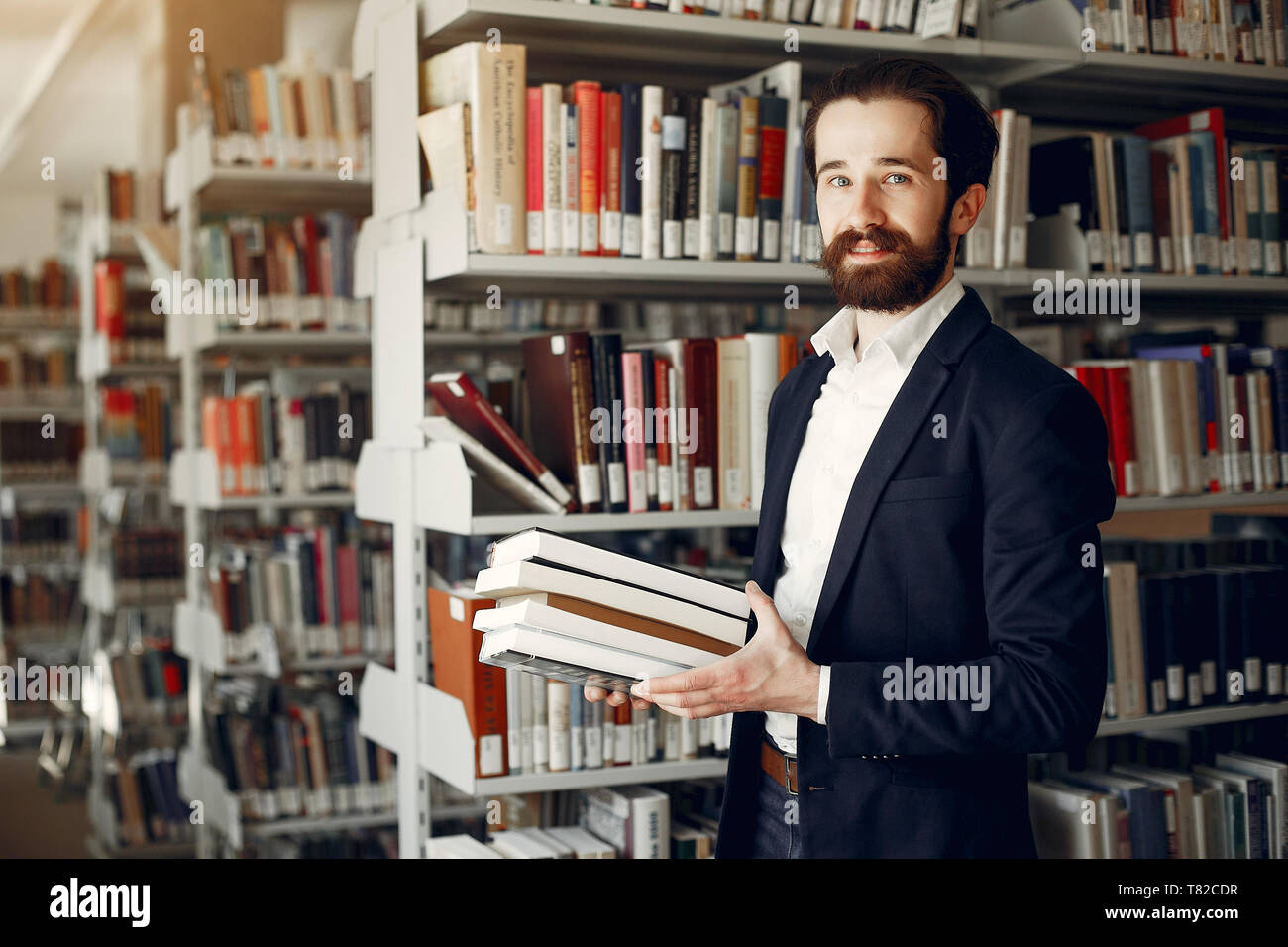 Man in a library. Guy in a black suit. Student with a books Stock Photo ...