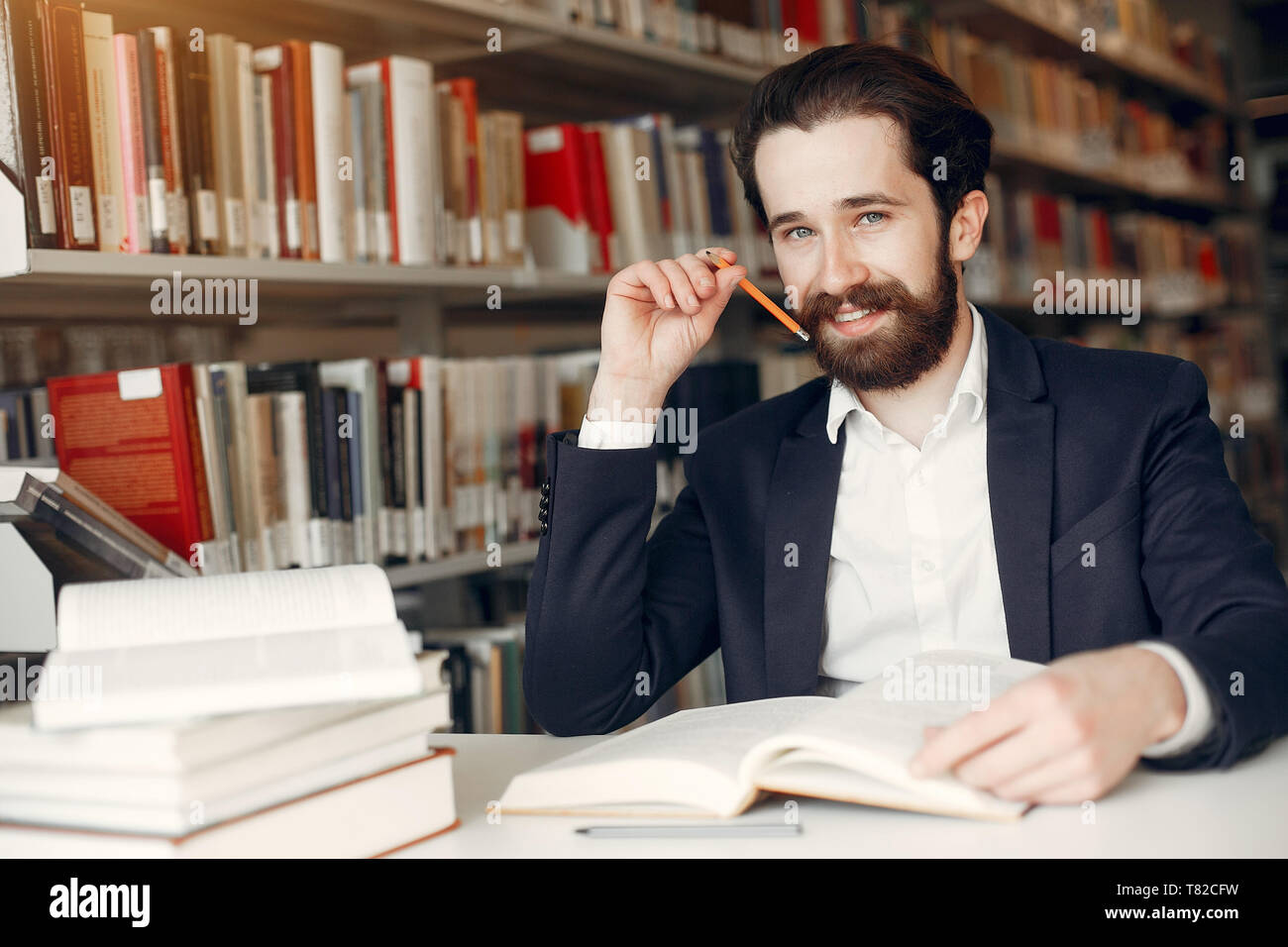 Man in a library. Guy in a black suit. Student with a books Stock Photo ...