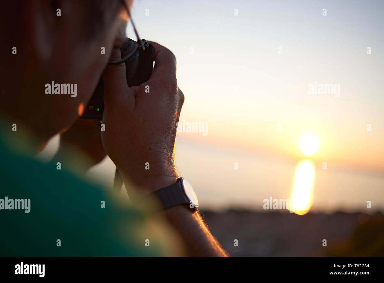 Over the shoulder of a man taking pictures using a DSLR camera during ...