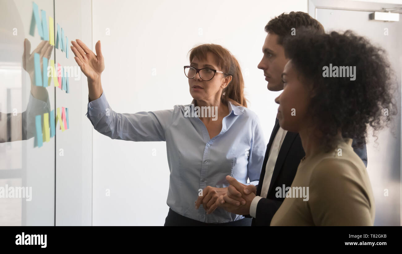 Female team leader explain project to colleagues with sticky notes ...