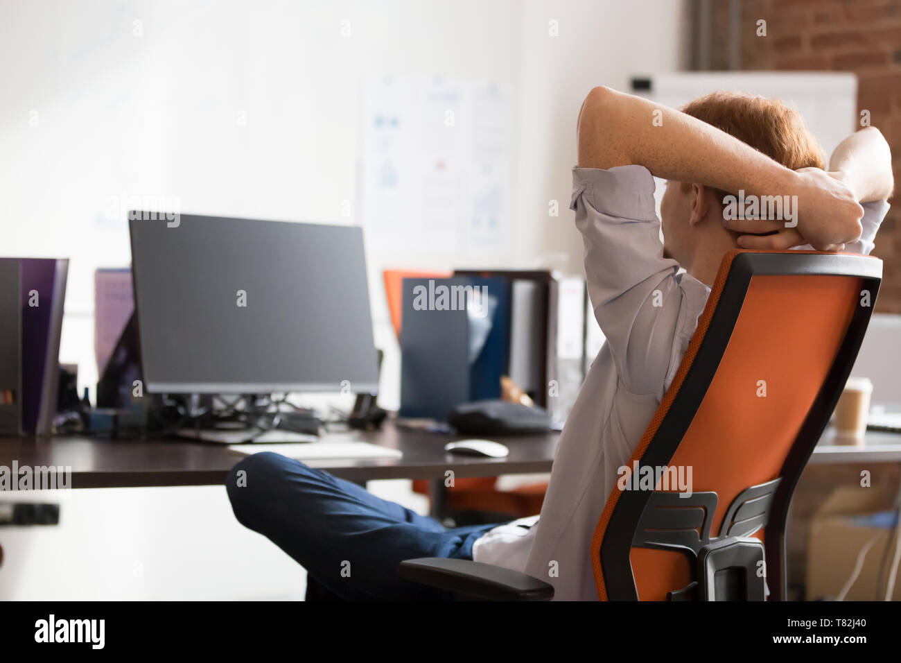Back view or redhead male employee relax in office chair Stock Photo ...