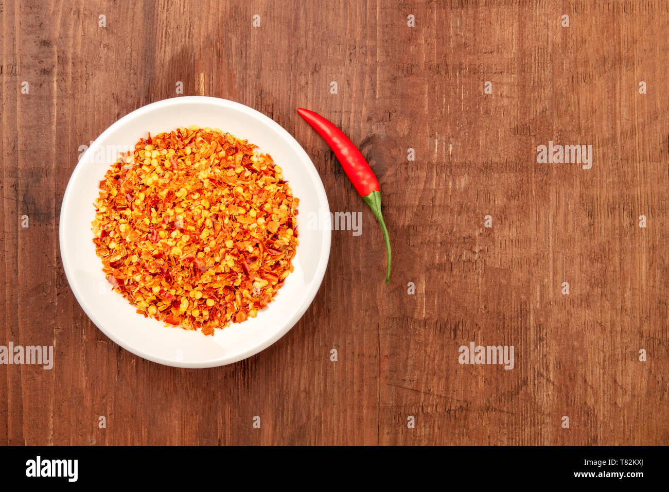 Red hot cayenne pepper, crushed, and a fresh chili, shot from above on ...