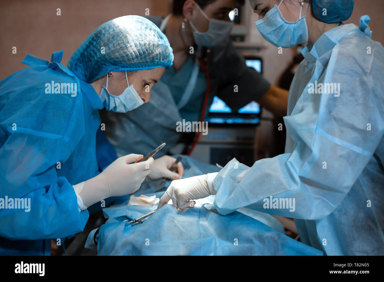 A female surgeon with an assistant performs surgery without incisions ...