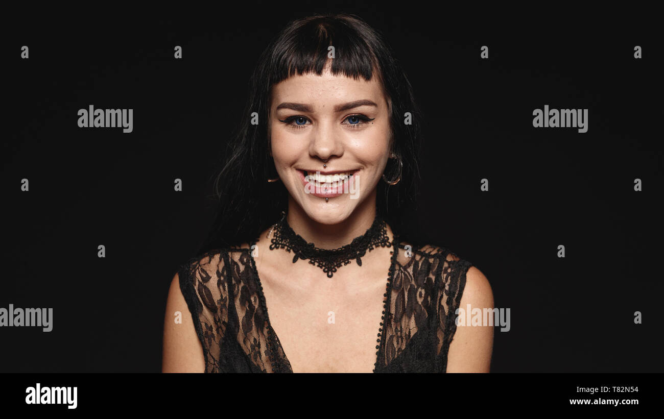 Smiling woman with fashion piercing on lips isolated on black ...