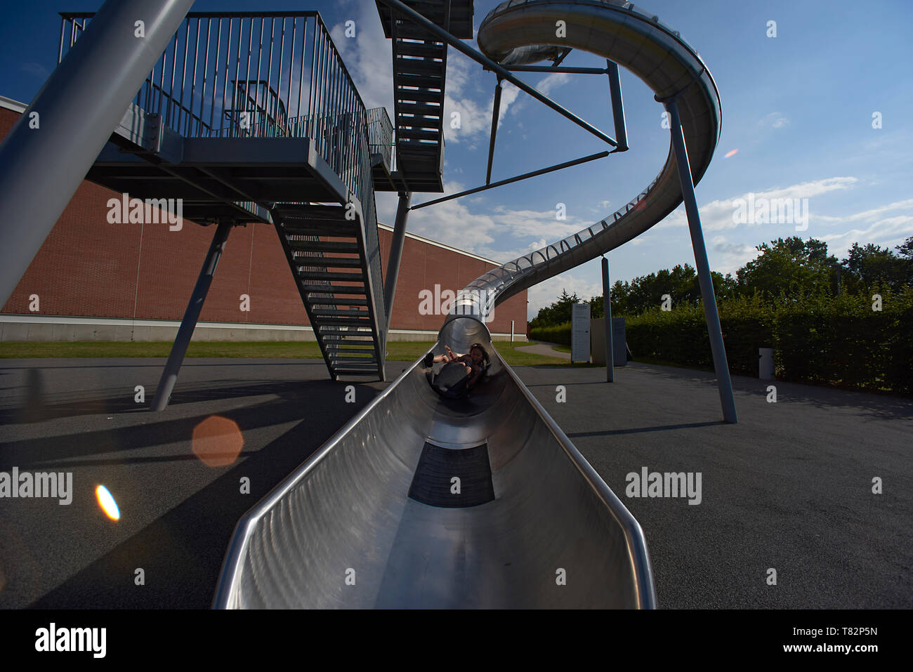 Kids enjoying the beautiful big metal slide at a playground in a park ...