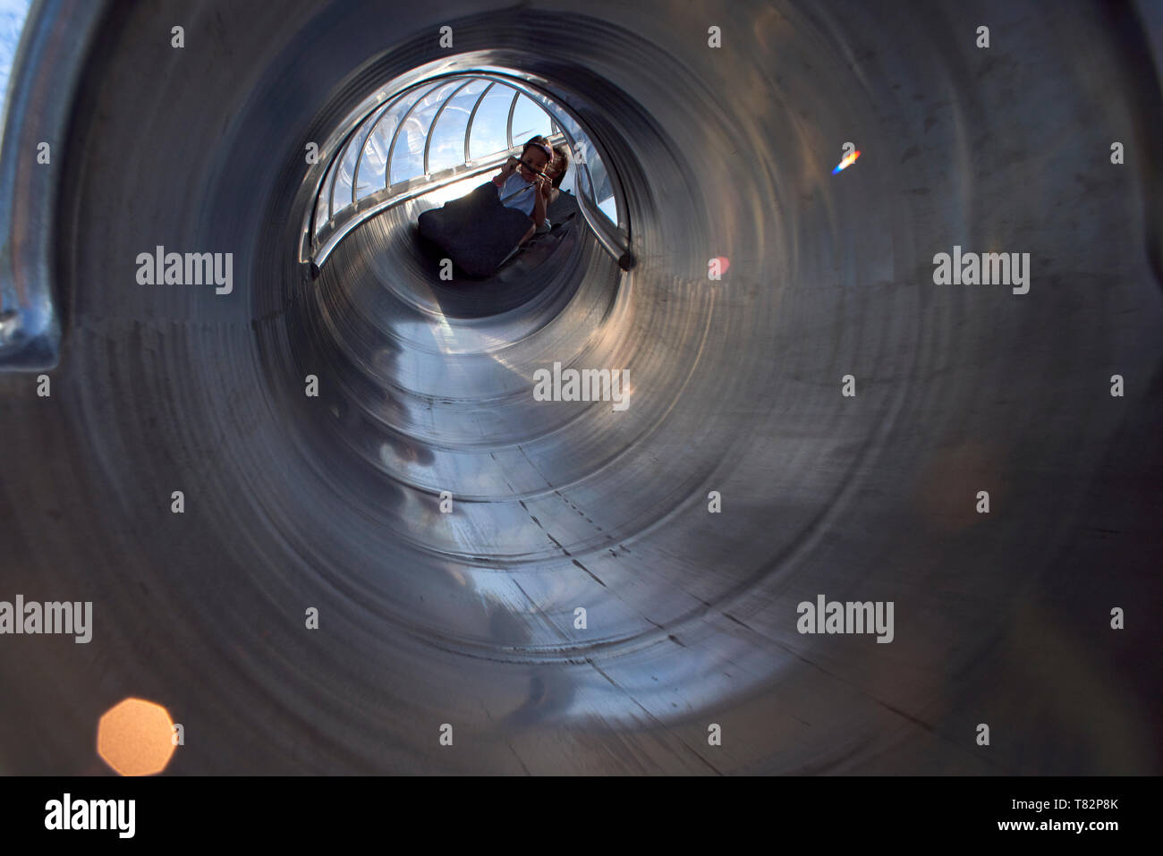 Kids enjoying the beautiful big metal slide at a playground in a park ...