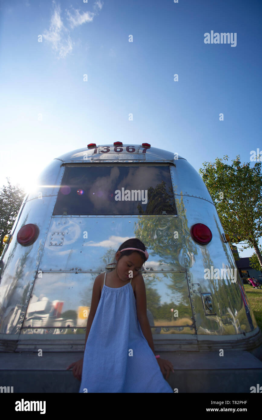 Cute young Asian girl posing in front of a metal American caravan in ...