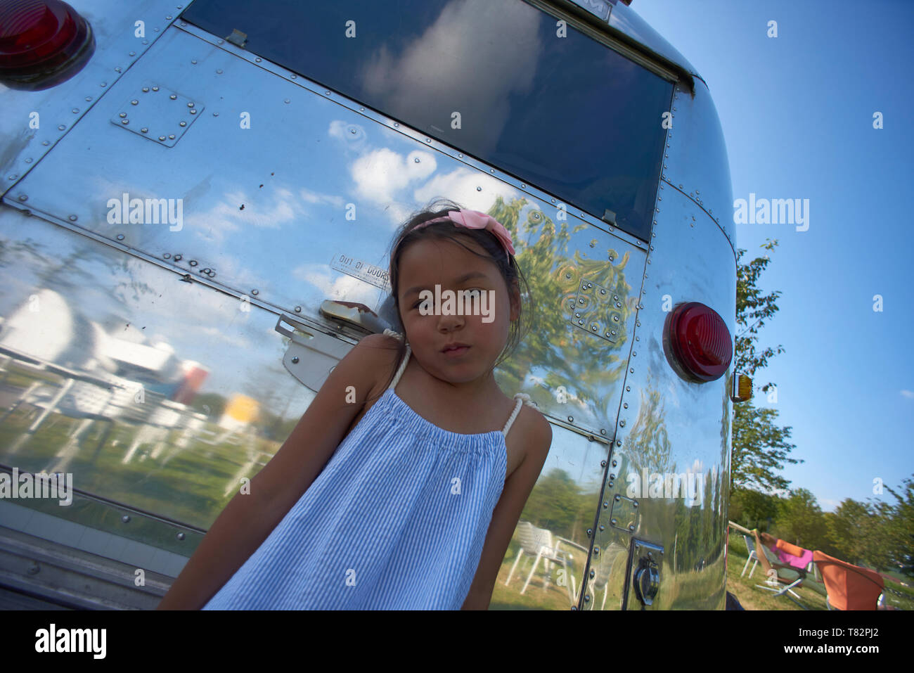 Cute young Asian girl posing in front of a metal American caravan in ...