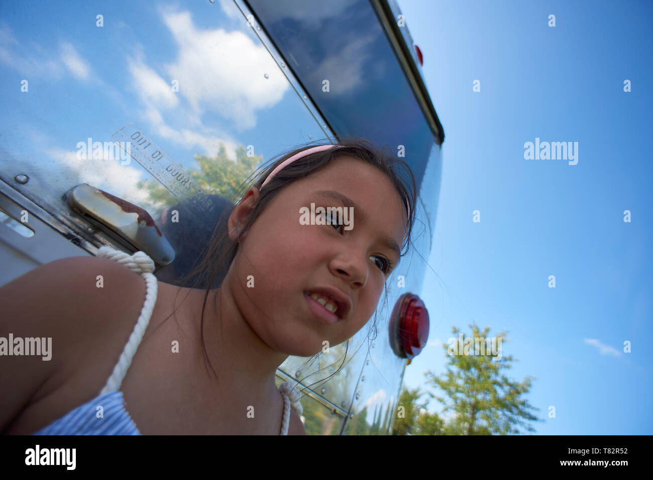 Cute young Asian girl posing in front of a metal American caravan in ...