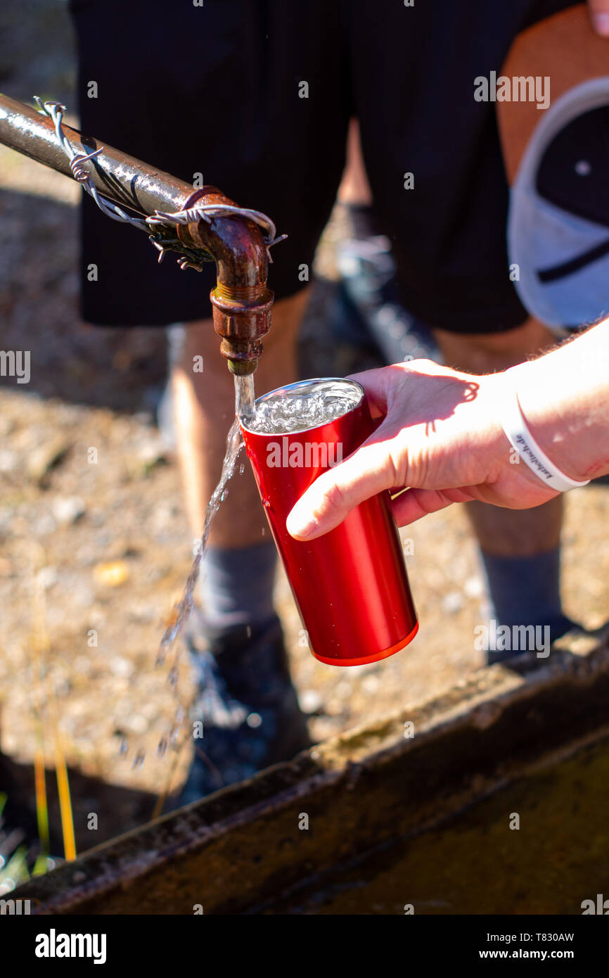 Backpacker drinking out of natural mountain spring water running out of ...