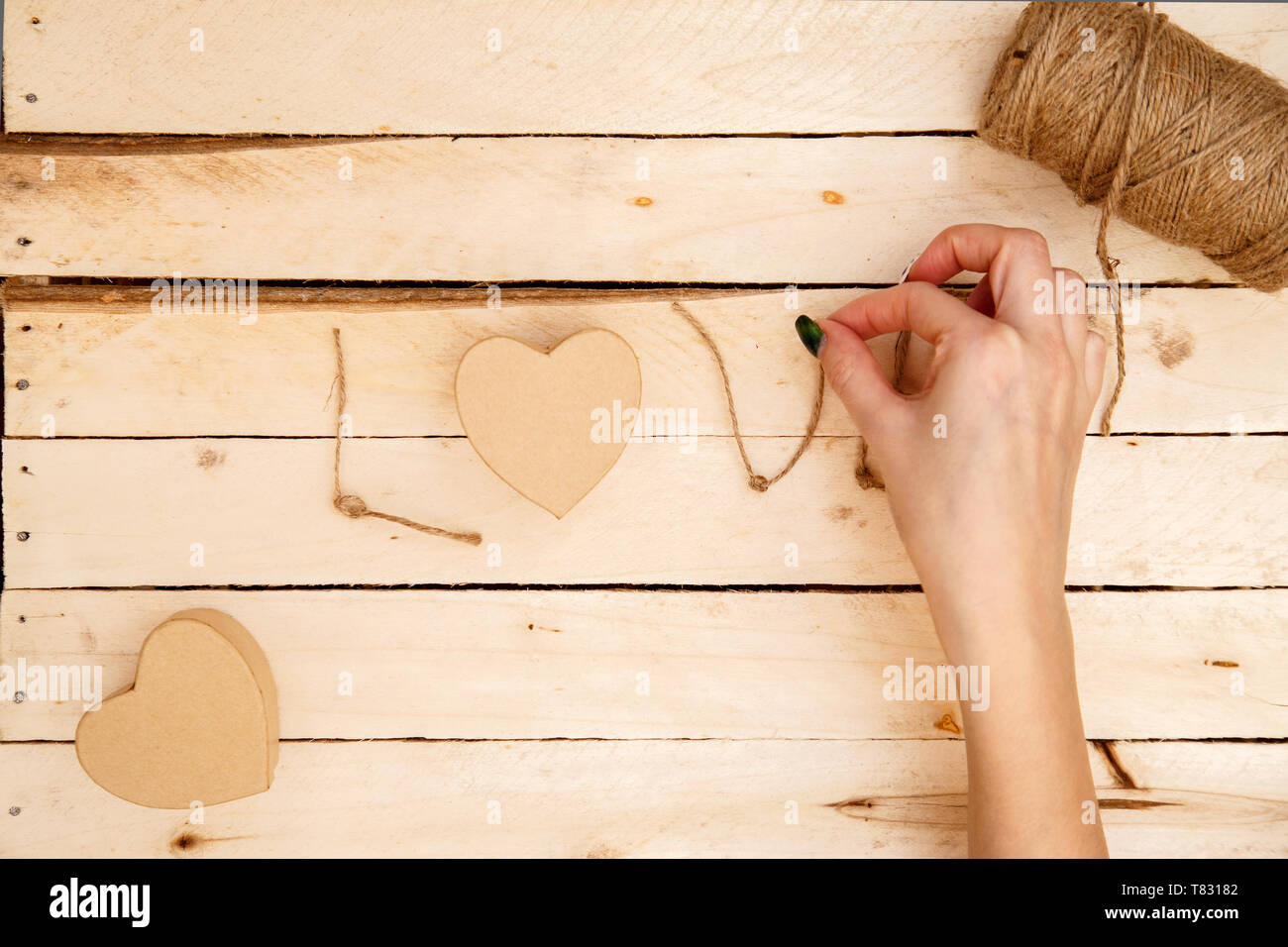 women's hands spread hearts and the word love of threads on a light ...