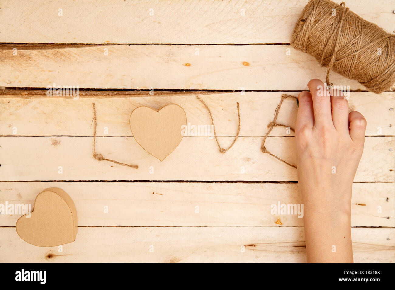 women's hands spread hearts and the word love of threads on a light ...