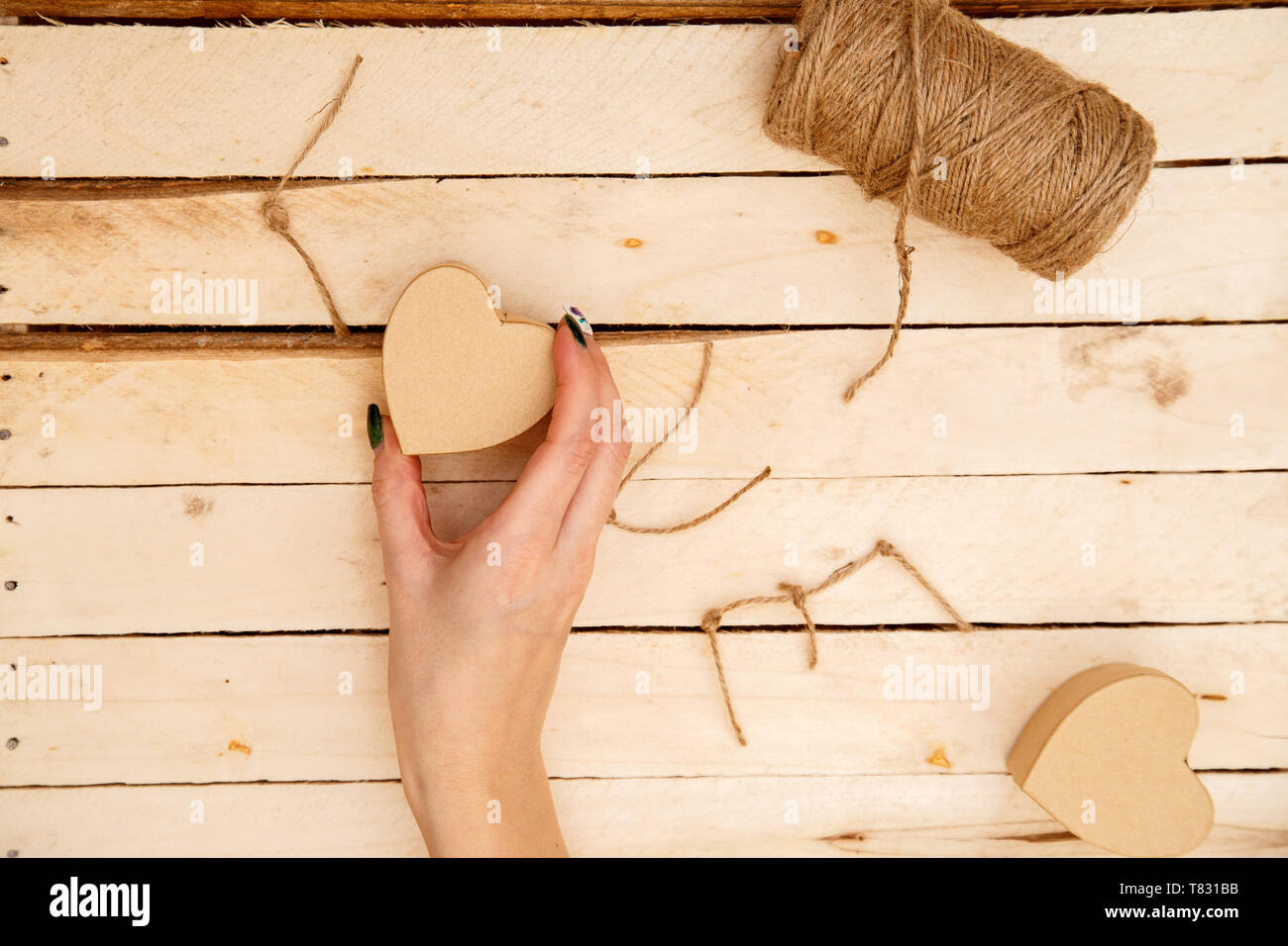 women's hands spread hearts and the word love of threads on a light ...