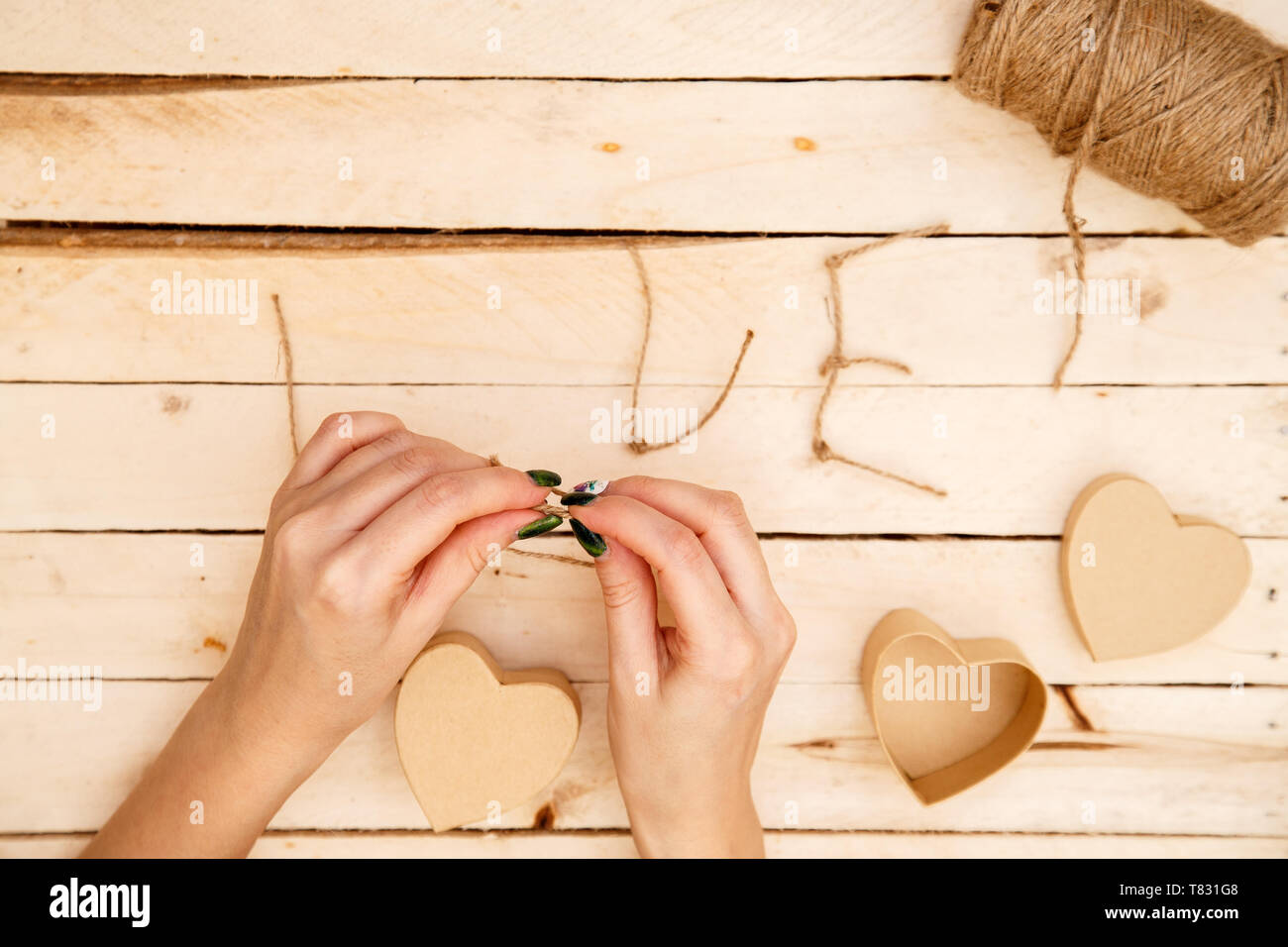 women's hands spread hearts and the word love of threads on a light ...